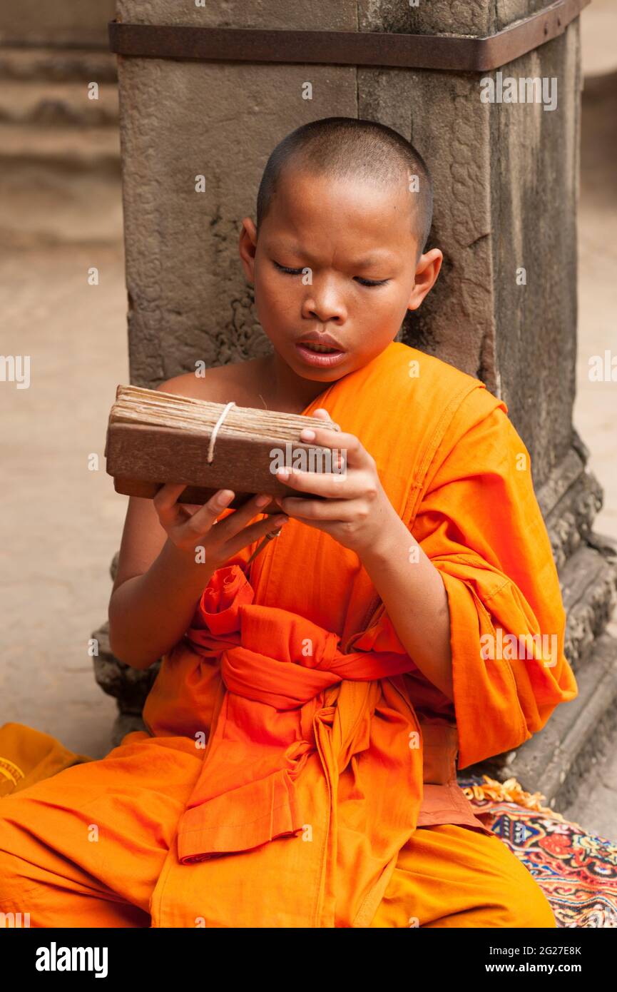 Young Buddhist monk reading from a wooden tablet at Angkor Wat. Siem ...