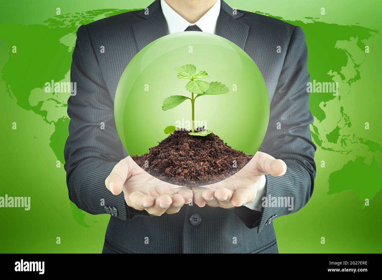 Businessman holding green sapling with soil inside the sphere ...