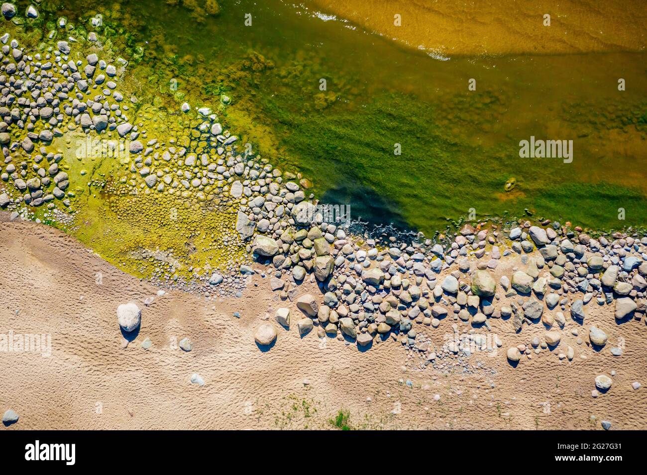 Aerial shot of the rocky Baltic seashore with green sea algae on stones ...
