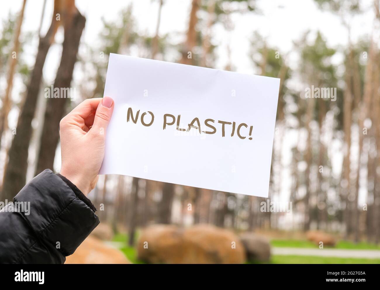 Female hands holding white paper sheet with text NO PLASTIC outdoors ...