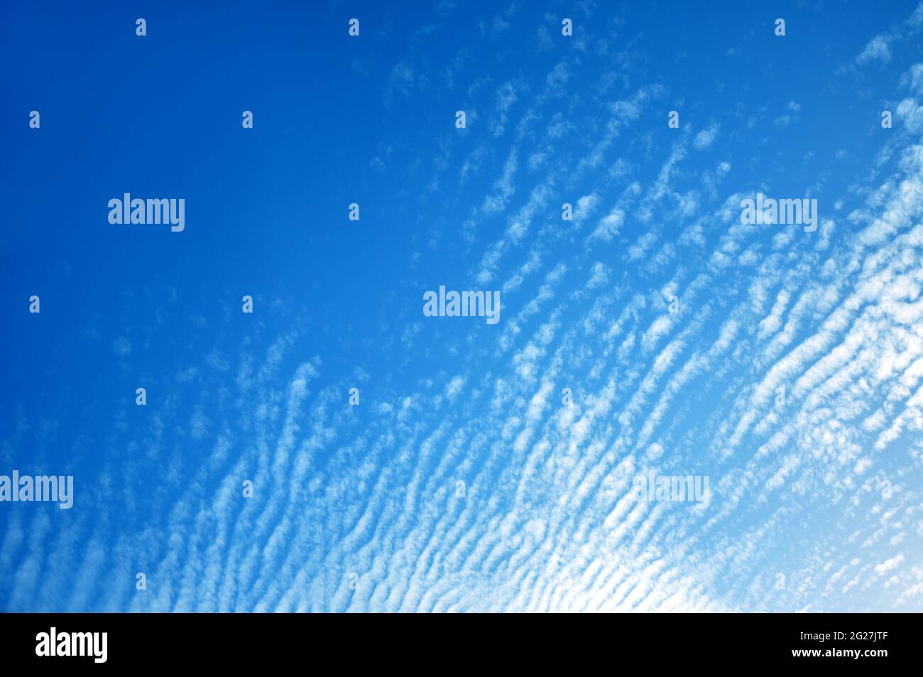 Blue sky with light scattered clouds Stock Photo - Alamy