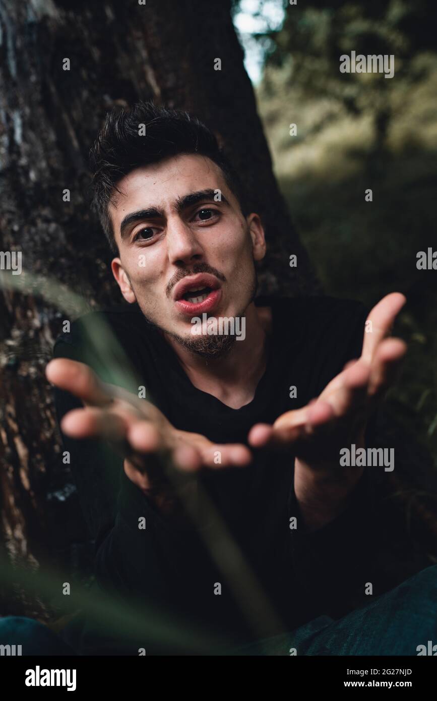 The young man leaning on a tree in the forest asks why, nature and ...