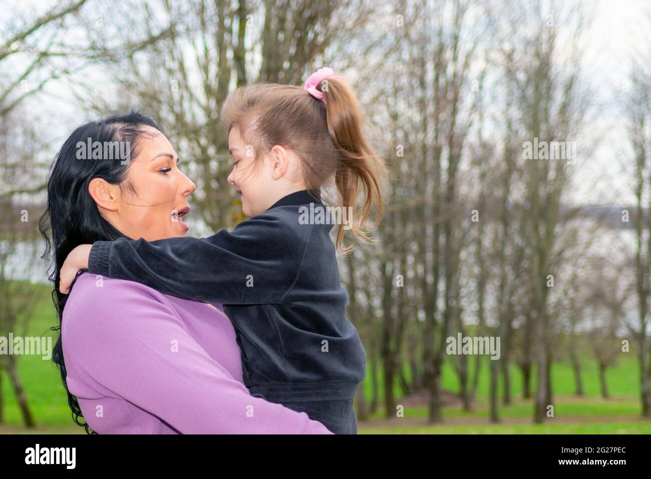 Beautiful mother and daughter play hugs in a spring park nature in ...