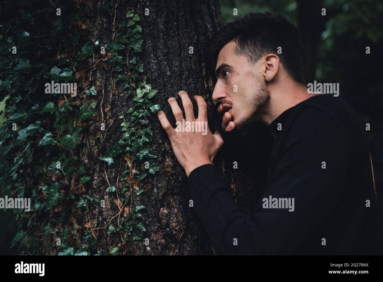 A young man in the forest hugging the trees and screaming and ...