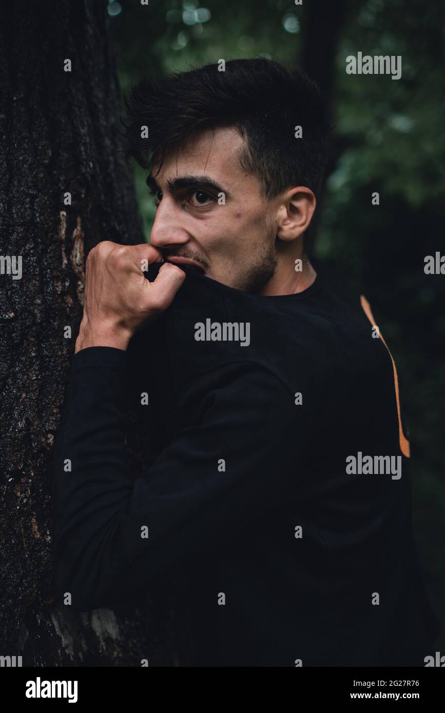 A young man in the forest hugging the trees and screaming and ...
