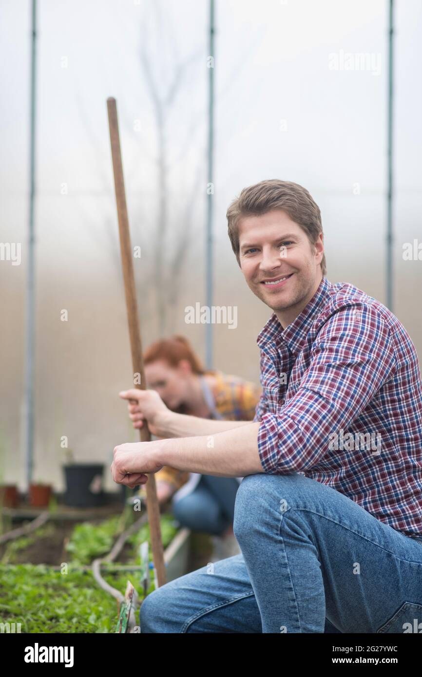 Man with rake crouched near garden bed Stock Photo - Alamy