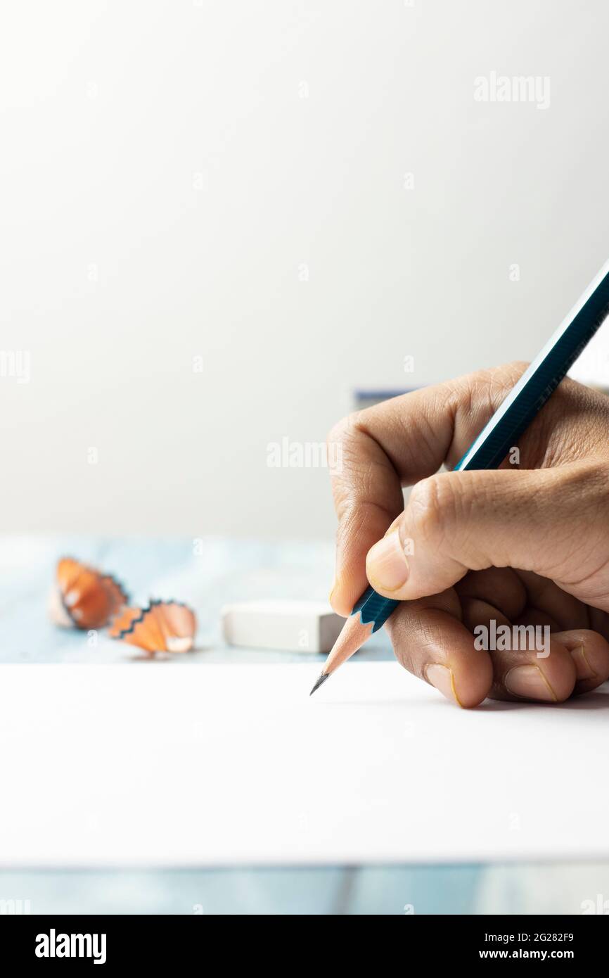 Close up view of hand and pencil writing on paper and white background ...