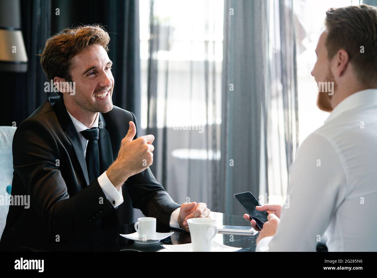 Colleagues and friends. Two cheerful businessmen drinking coffee and ...