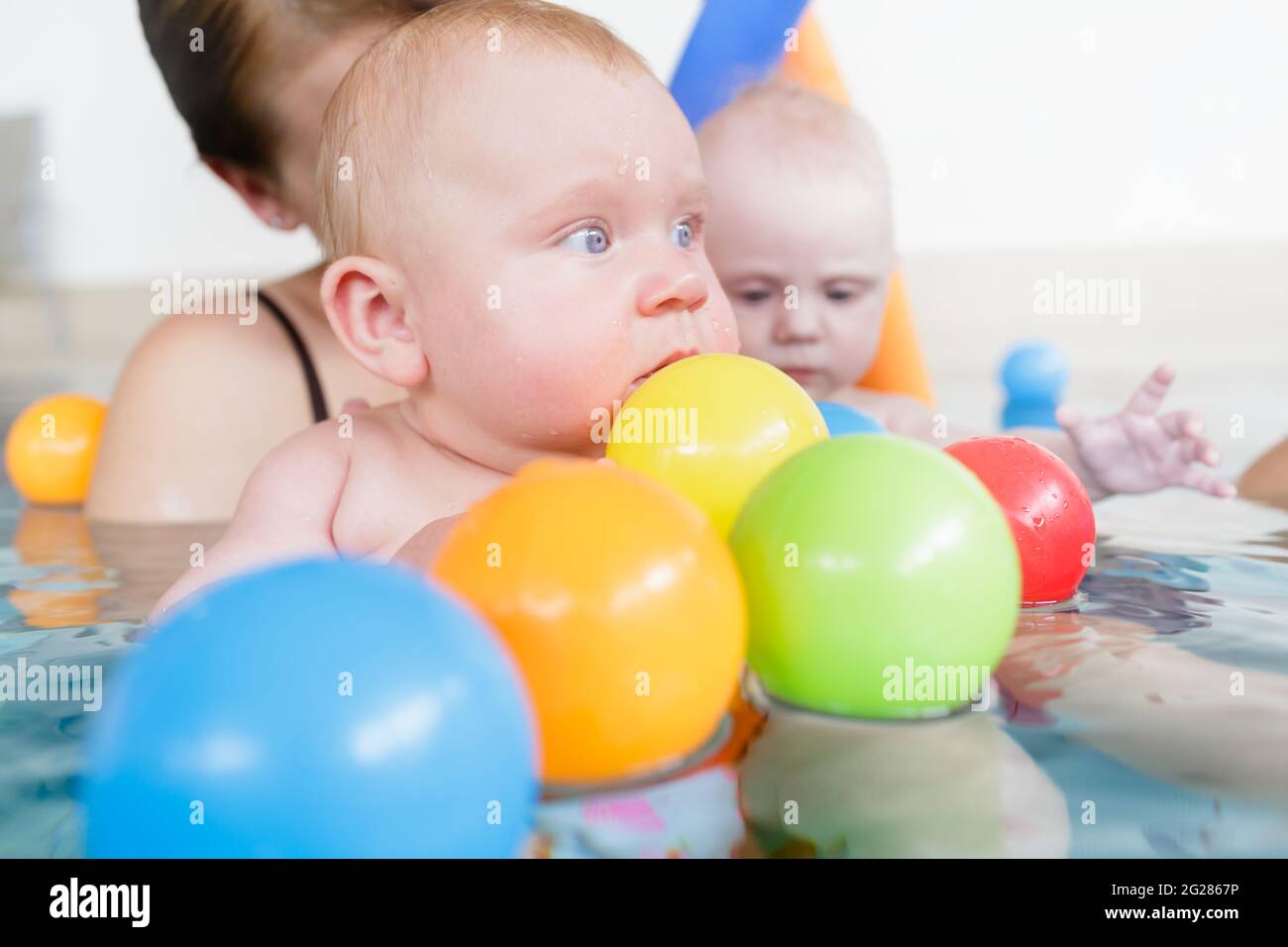 Mothers and their kids having fun at baby swimming lesson between lots ...