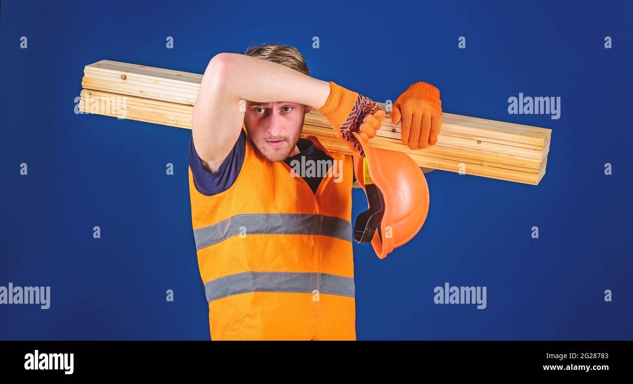 Tired labourer concept. Man in helmet and protective gloves wiping ...