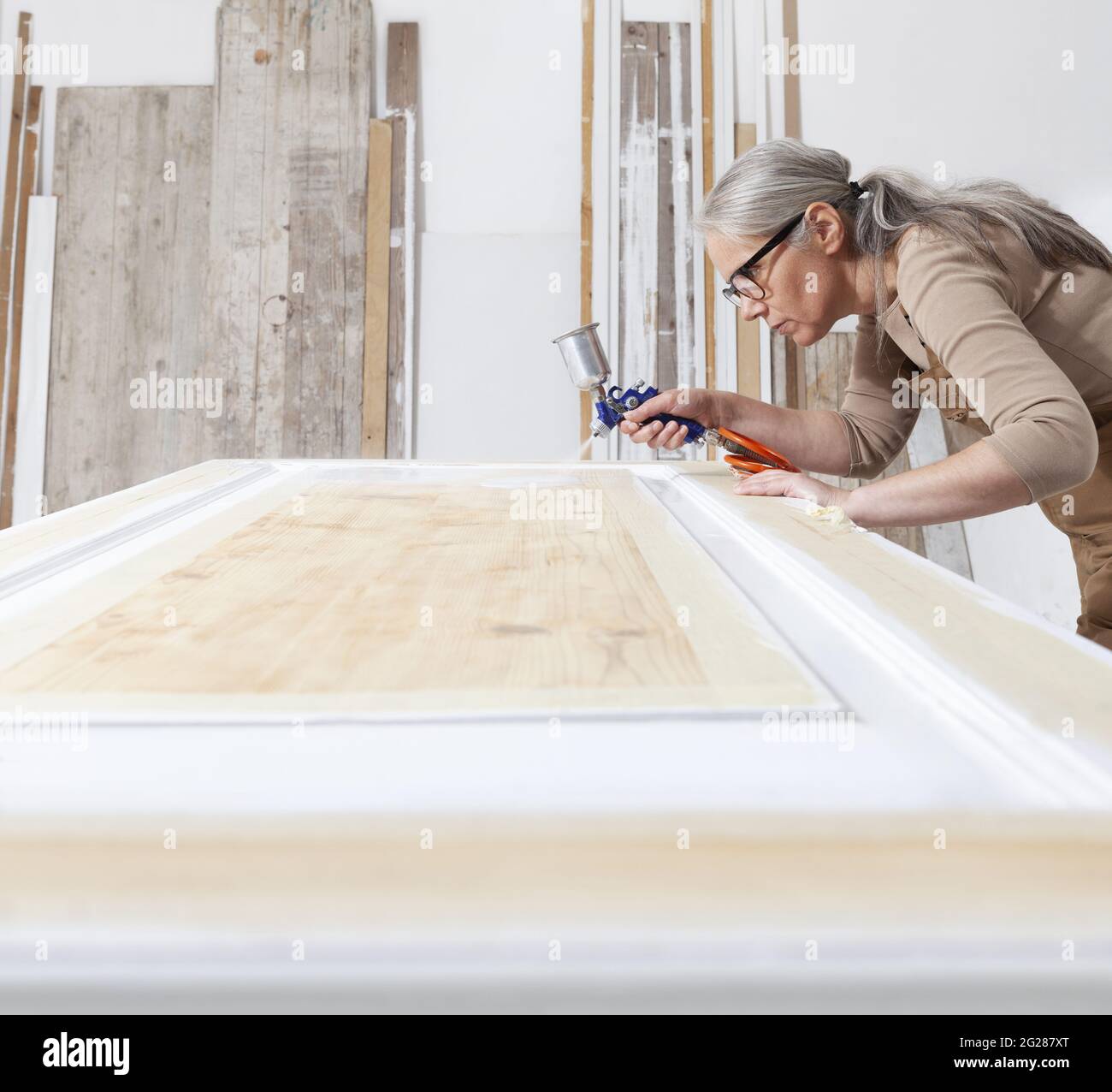wood crafts, woman artisan carpenter painting with spray gun paint ...