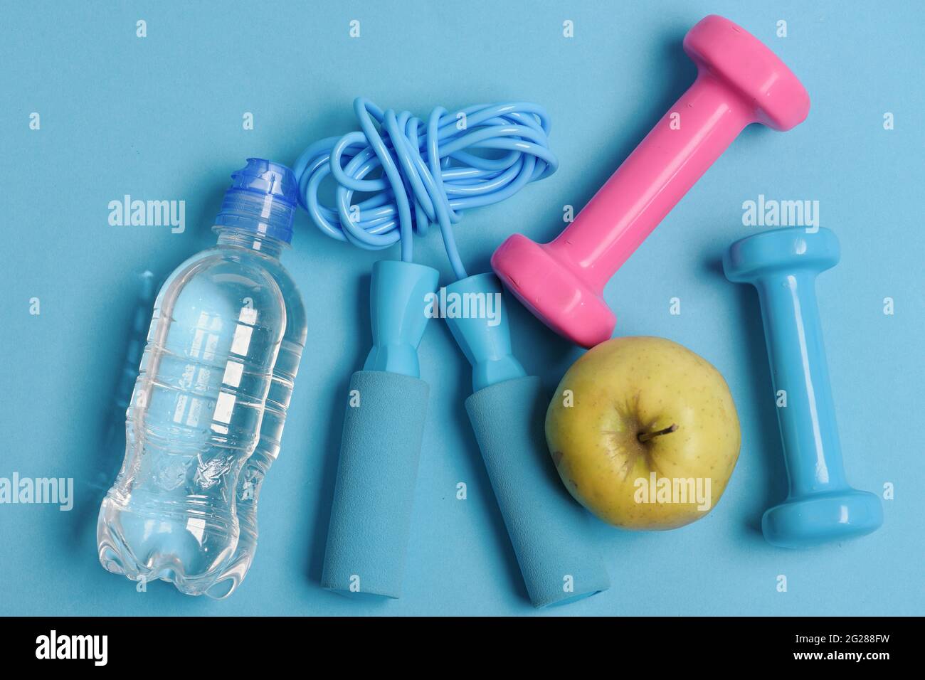 Jump rope, apple and barbells next to water bottle Stock Photo - Alamy
