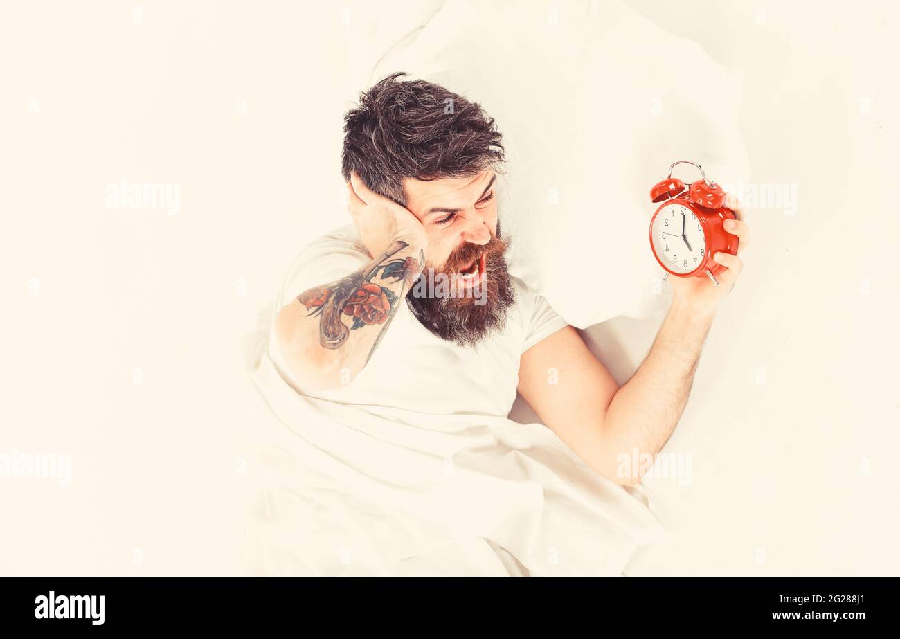 Man with tattoo and beard having trouble waking up Stock Photo - Alamy