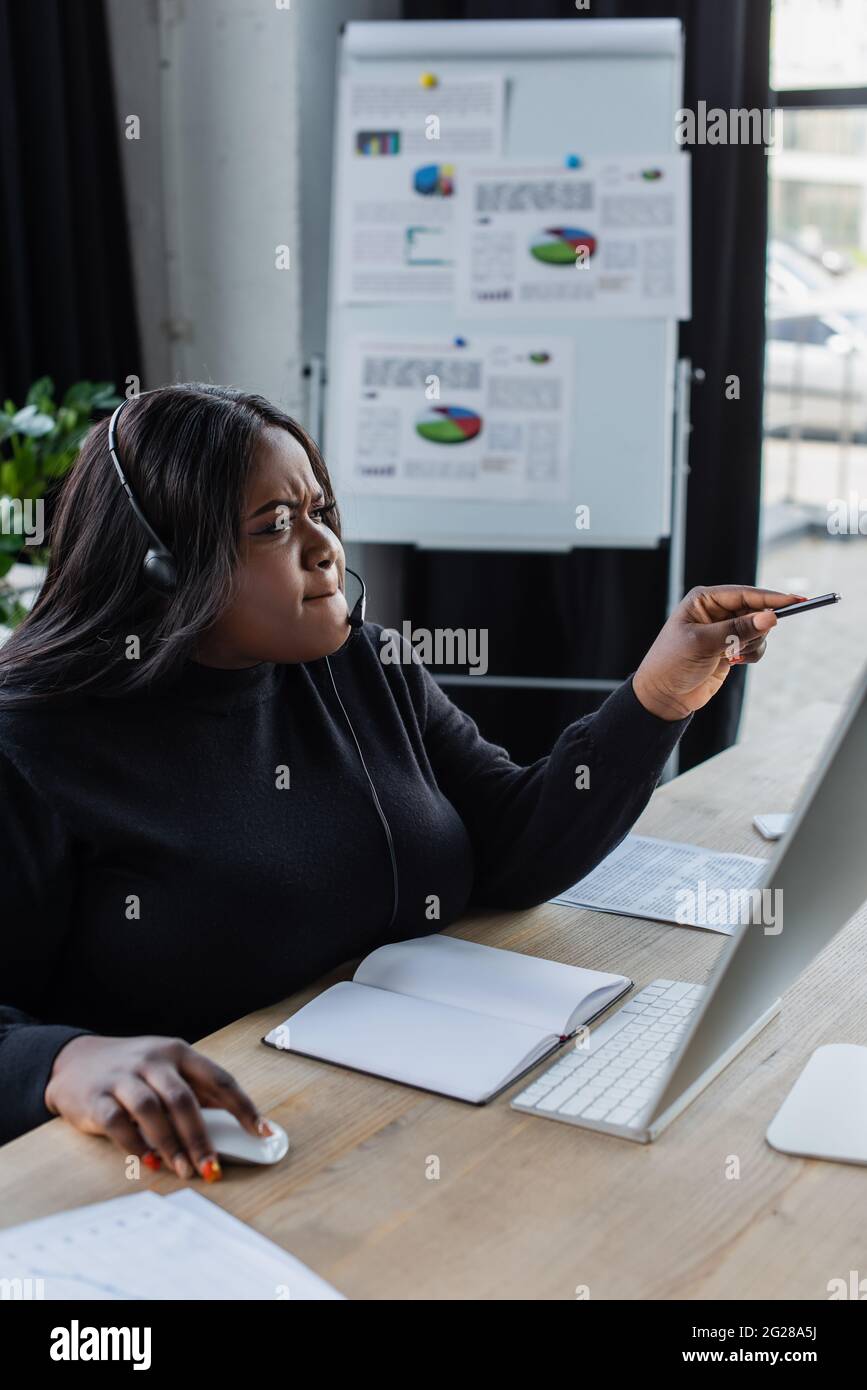 african american plus size operator in headset with microphone pointing ...
