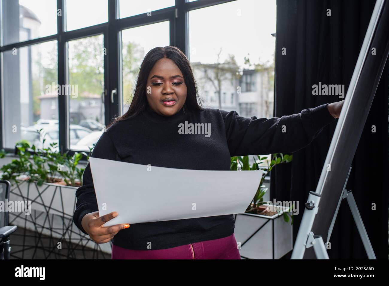 african american plus size businesswoman holding blank paper near flip ...