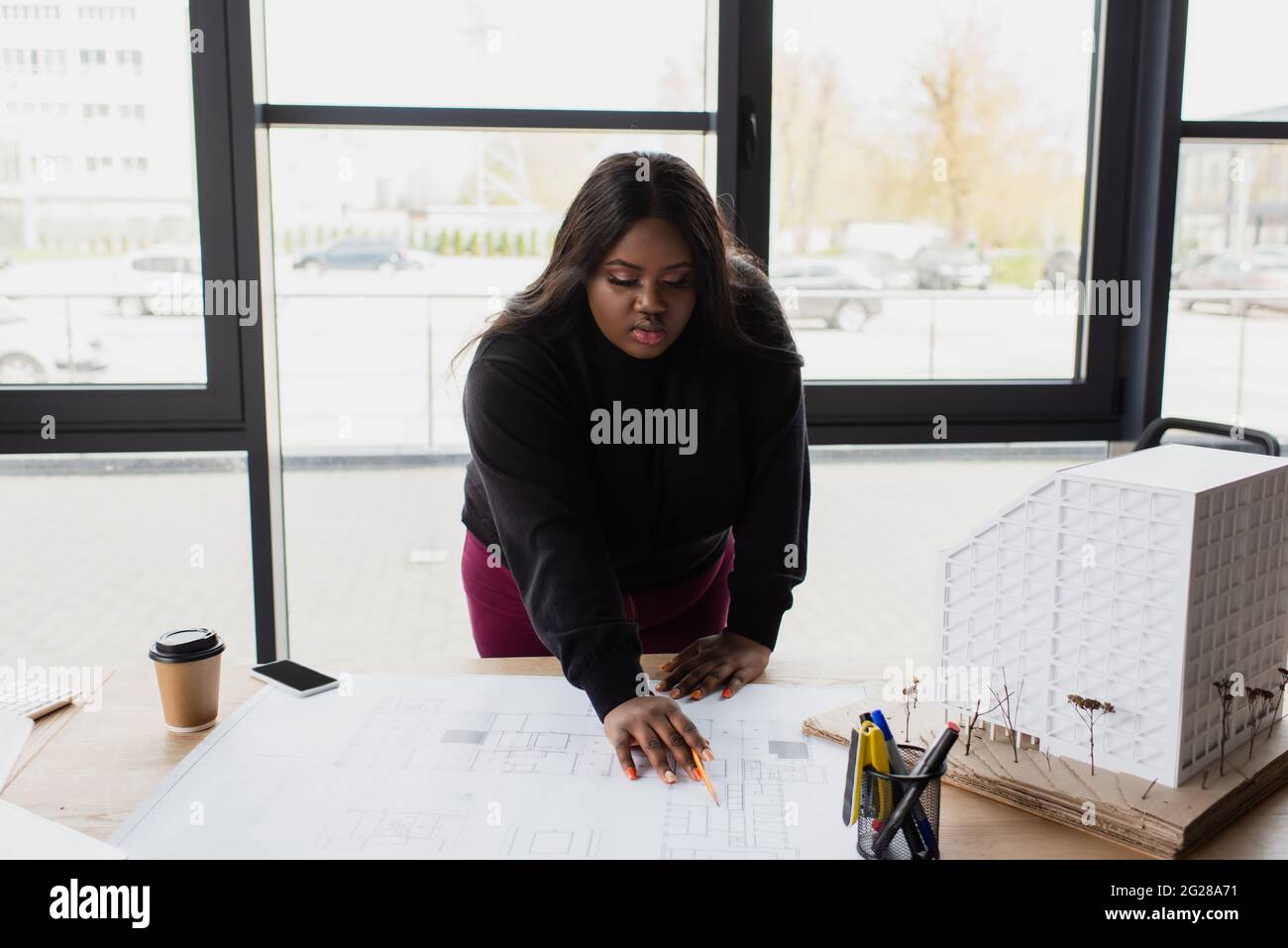 african american plus size designer looking at blueprint on desk with ...