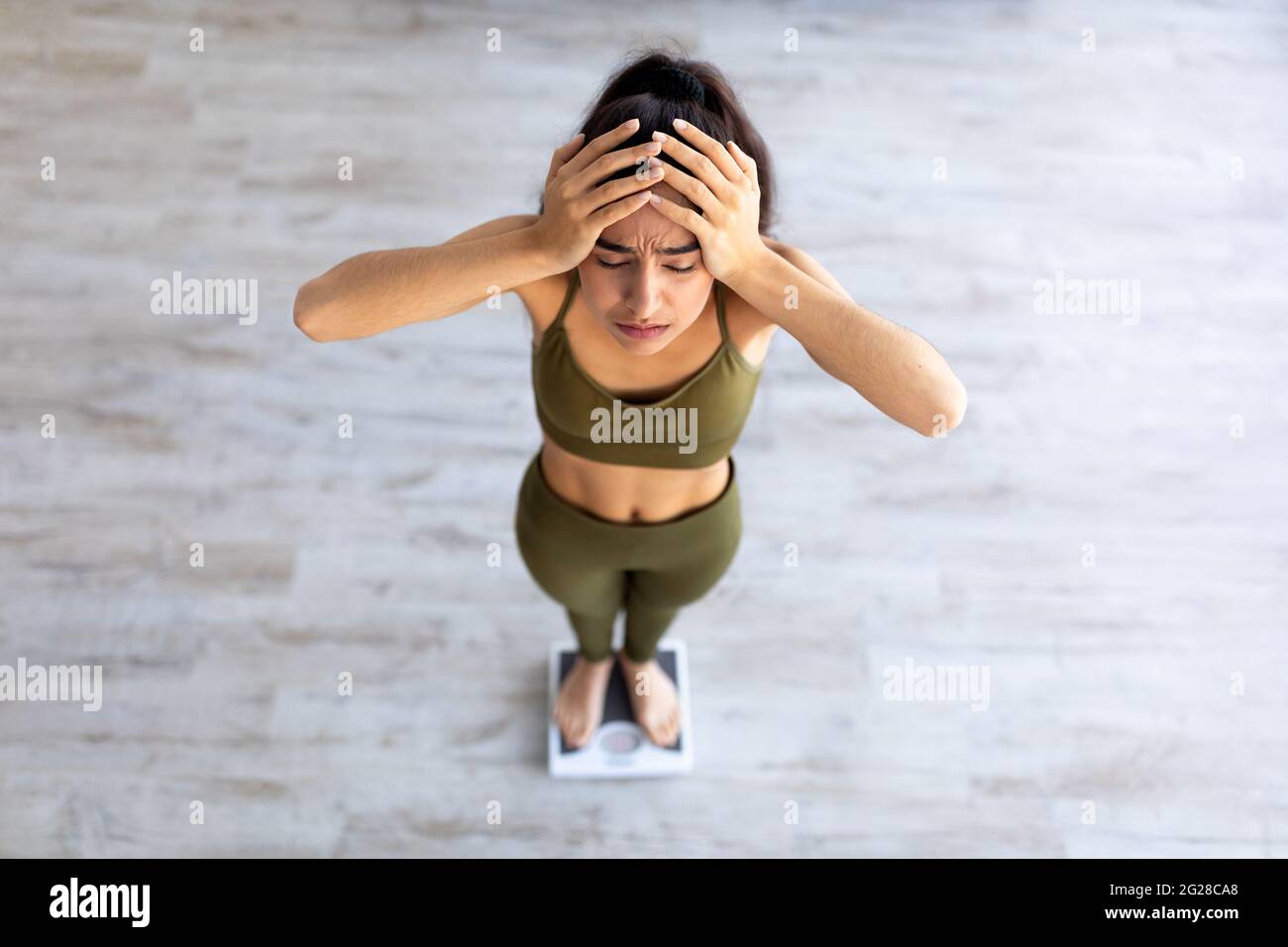 Upset young Indian woman unhappy about her weight, standing on scales ...