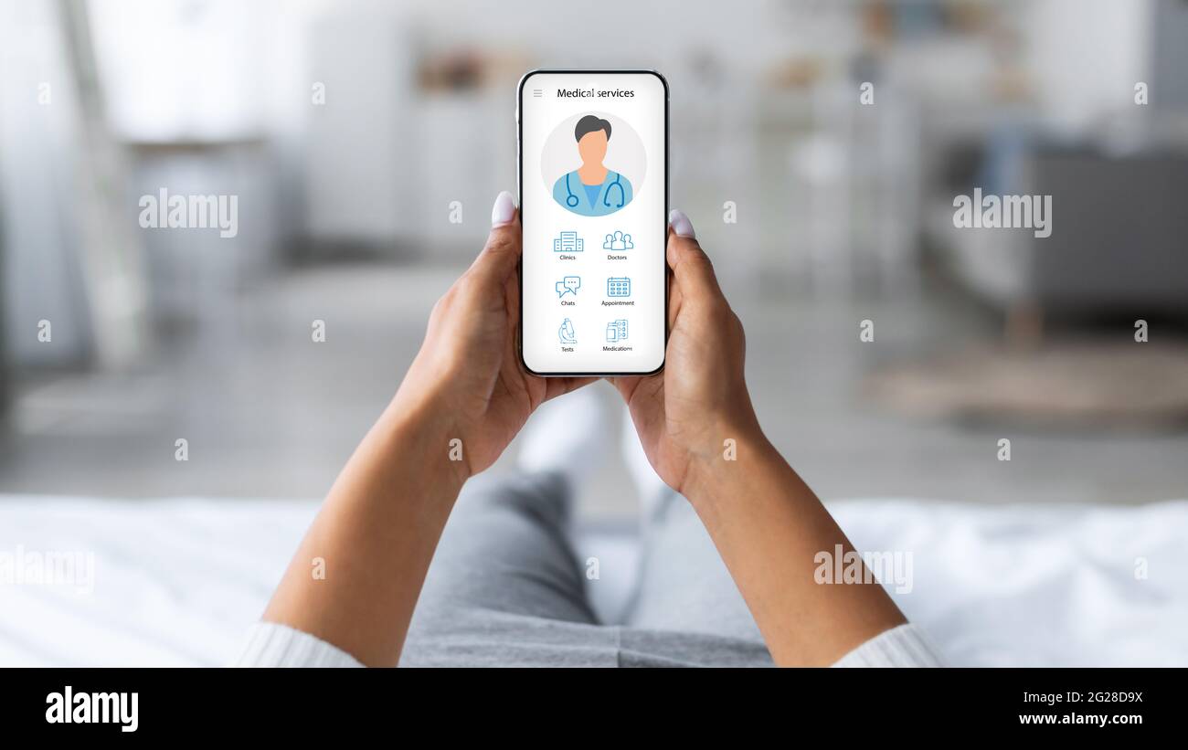 Woman laying on bed with mobile phone, using medical app Stock Photo ...