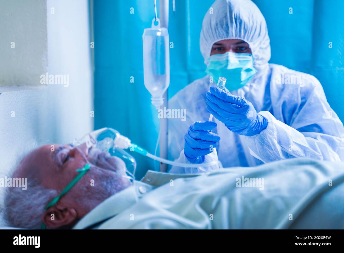 Doctor with protective suit preparing injection syringe while patient ...