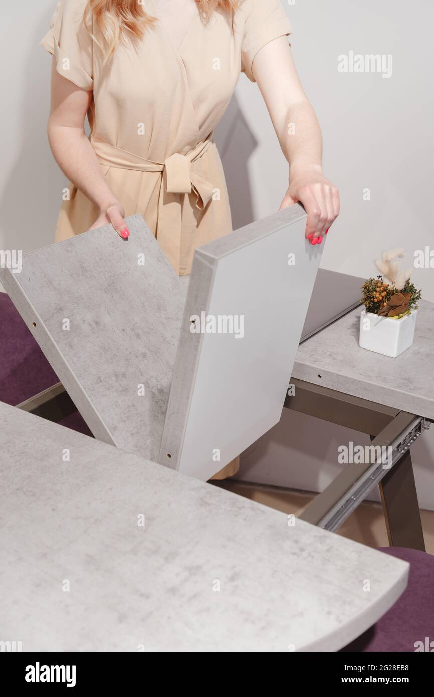 Woman setting up extendable dining table Stock Photo - Alamy