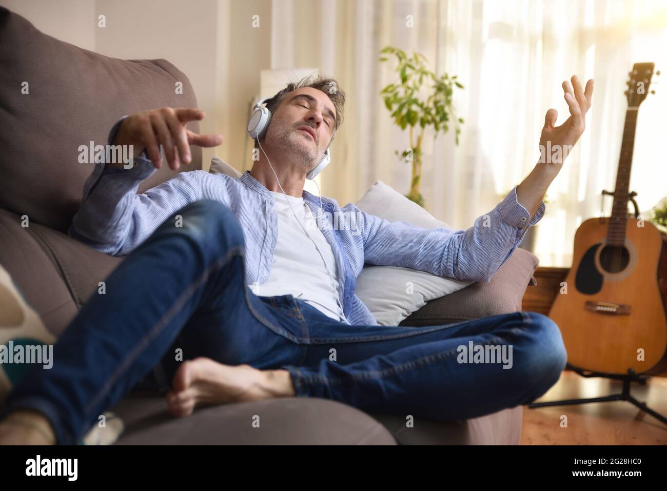 Man in the living room lying on the sofa absorbed listening to quiet ...