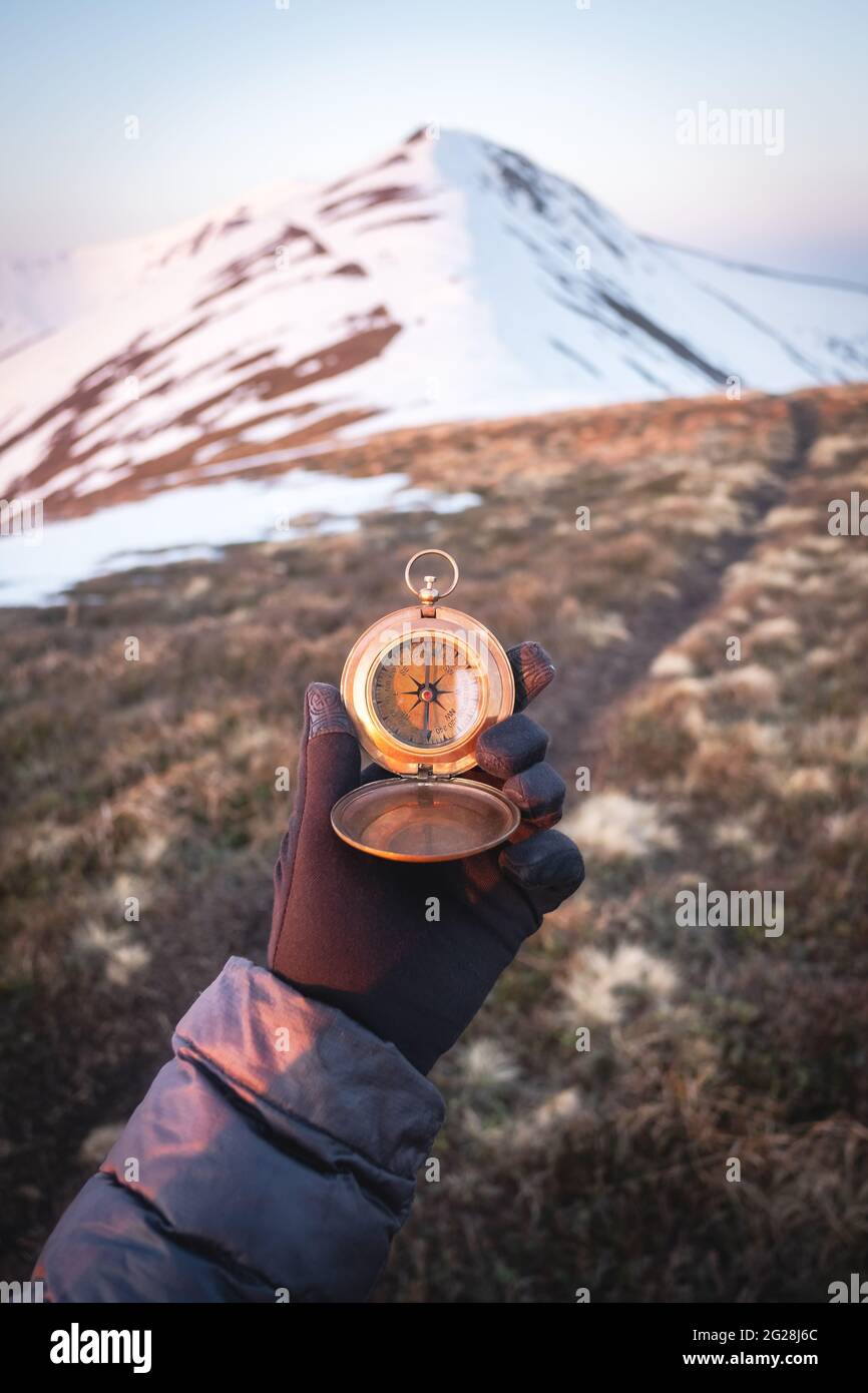 Man with retro compass in high snowy mountains on sunrise time. Travel ...