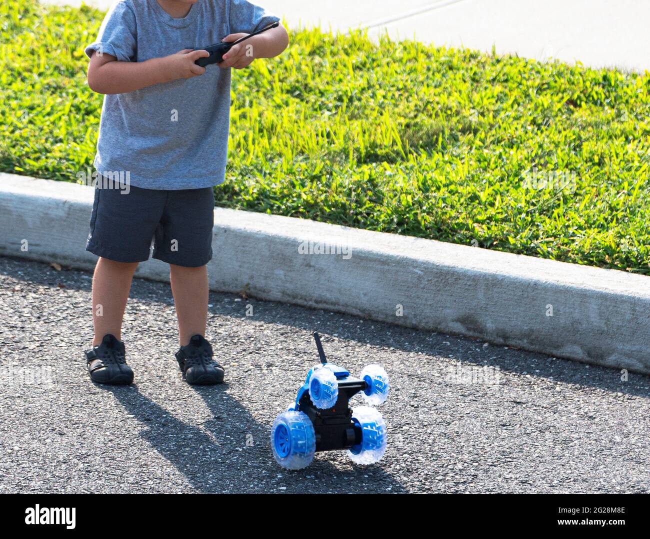 Child using remote controller with toy car in the street in front of ...
