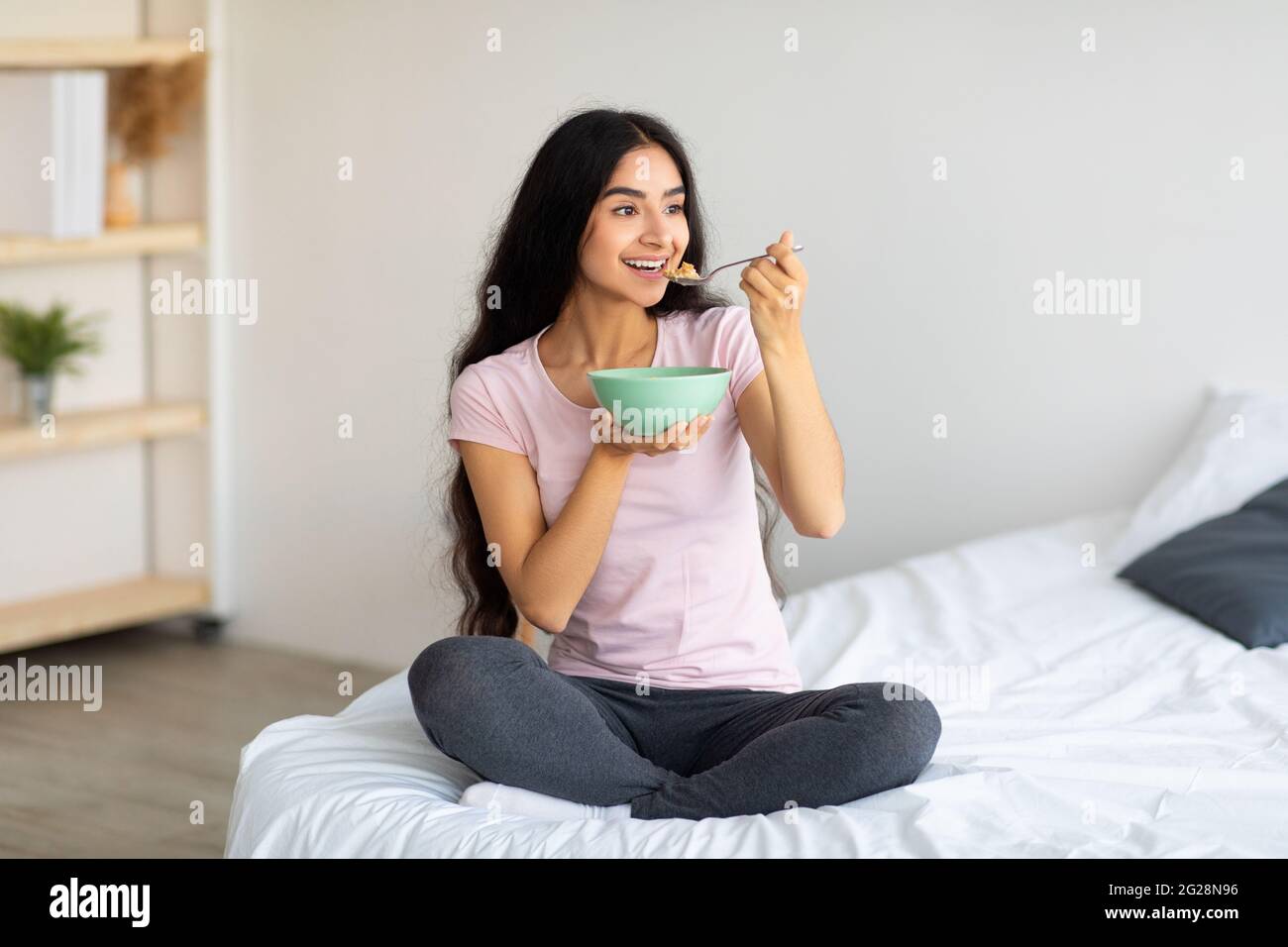 Attractive Indian lady eating yummy cereal with milk while sitting on ...