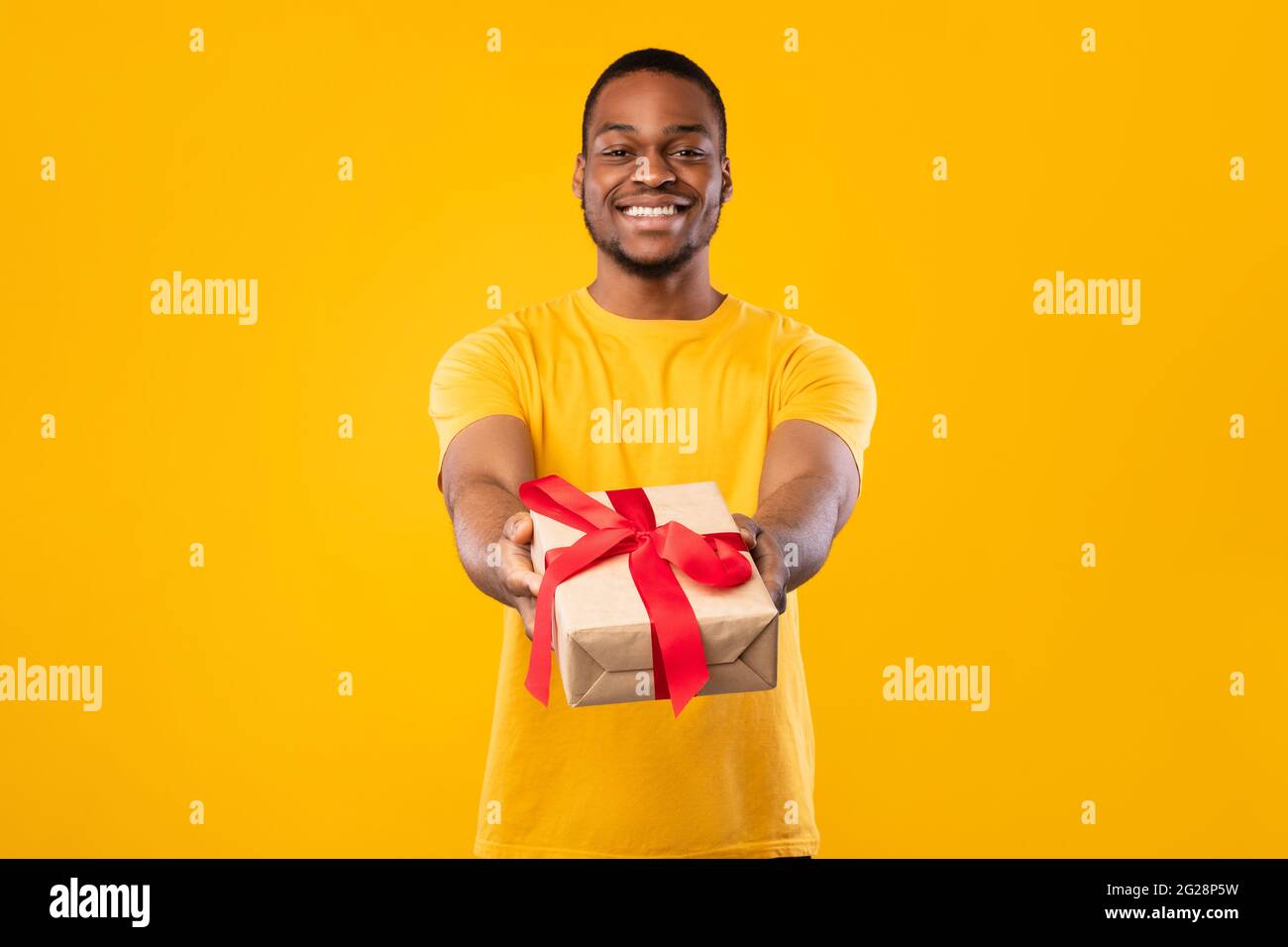 Black Guy Giving Wrapped Present Box To Camera, Yellow Background Stock ...