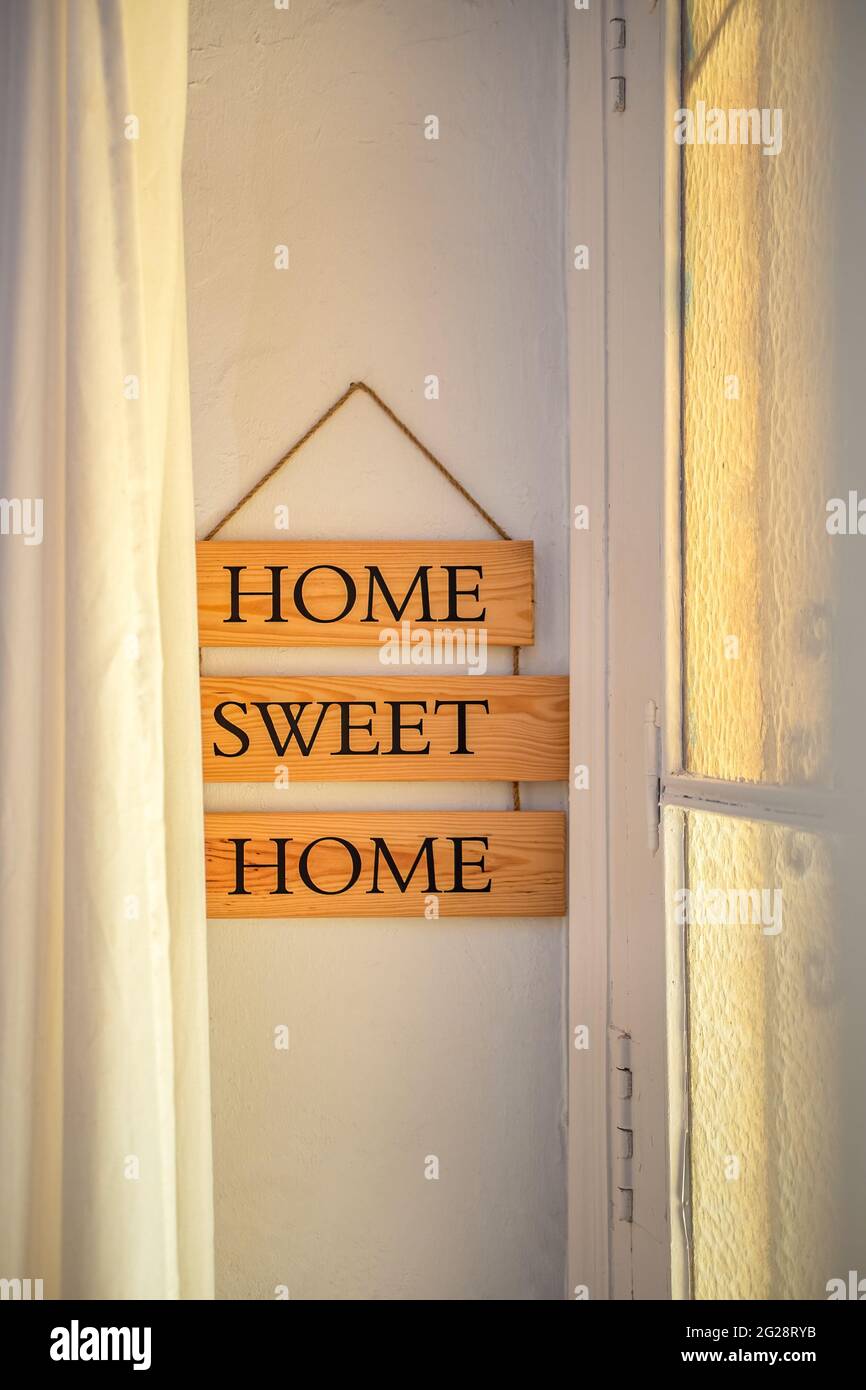 Home sweet home text on a wooden nameplate at the entrance to a house ...