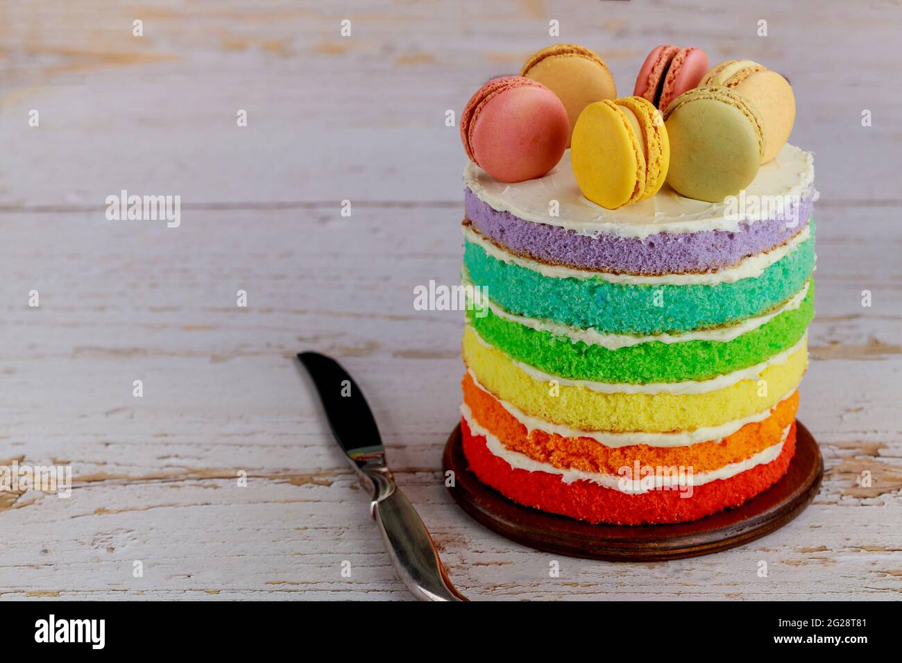 Rainbow birthday cake decorated with color macaroons Stock Photo - Alamy
