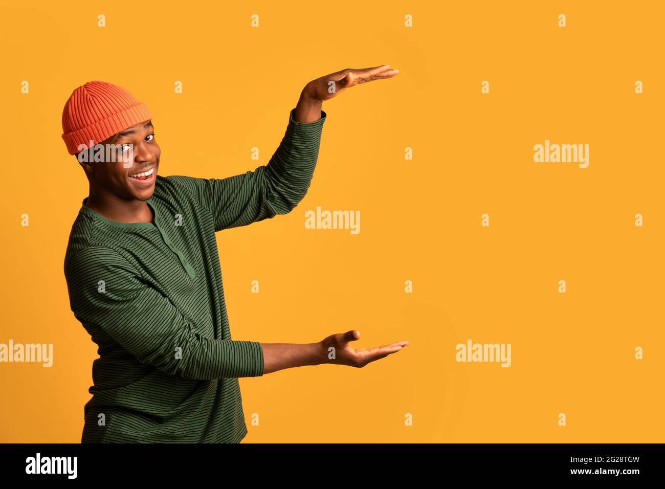 Positive Black Guy Holding Big Invisible Object In Hands Over Yellow ...