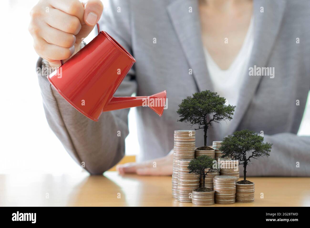 hand business woman and red watering can with money Stock Photo - Alamy