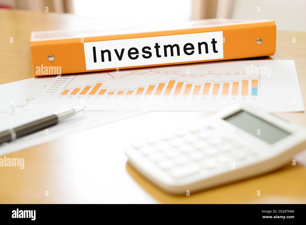 Orange binder investment on desk in the office with calculator and pen ...