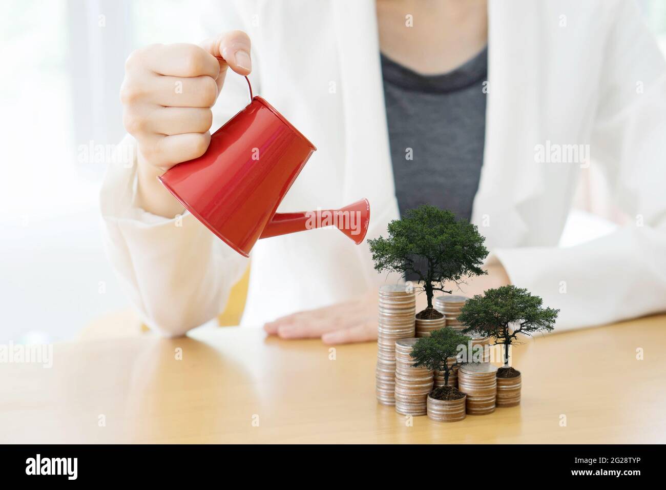 hand business woman and red watering can with money Stock Photo - Alamy