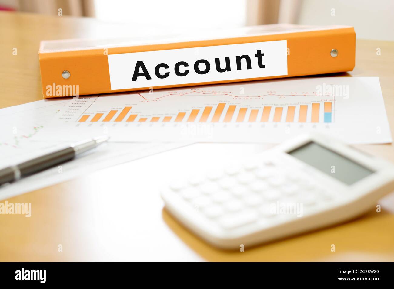 Orange binder account on desk in the office with calculator and pen ...