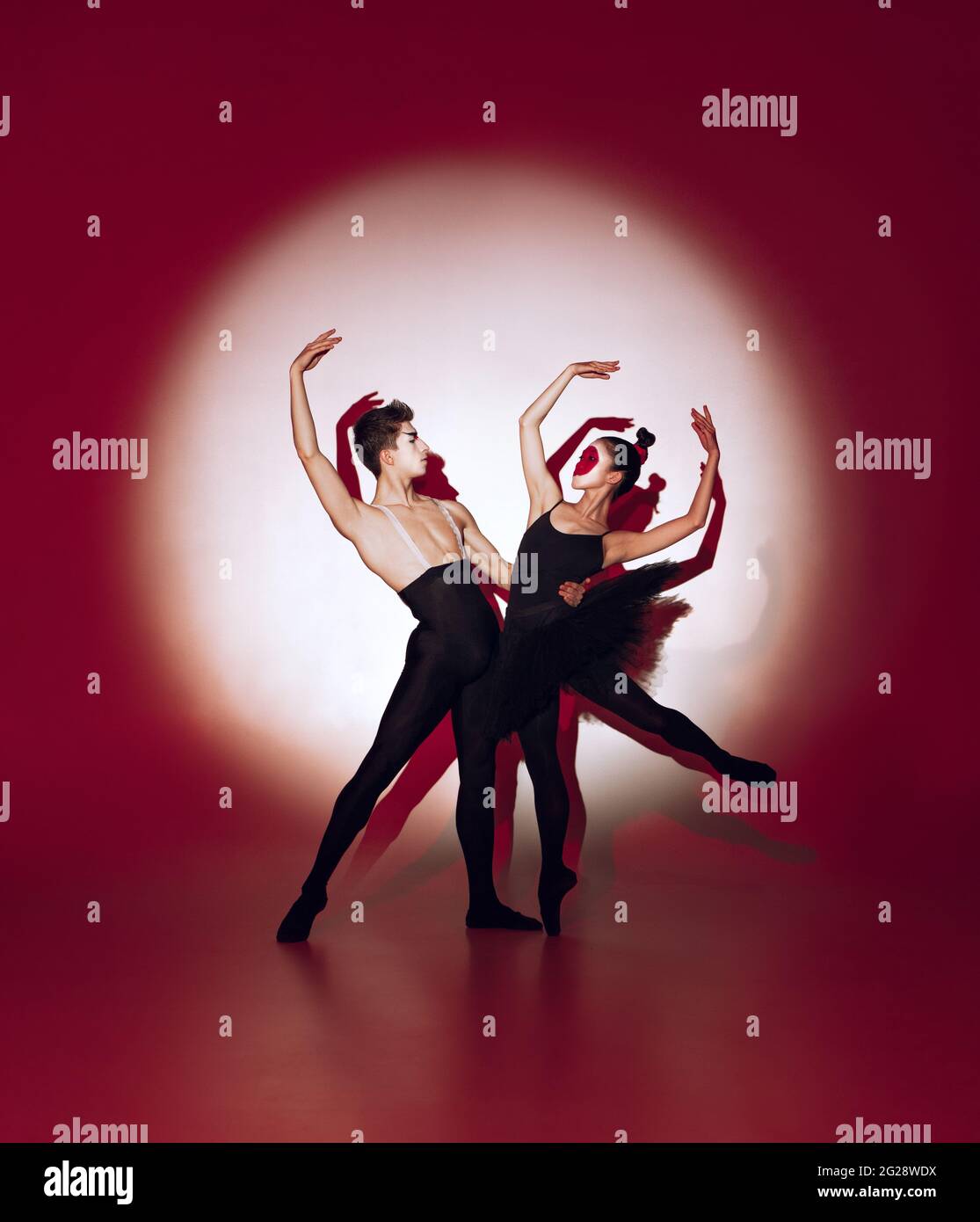 Ballet dancers dancing over red studio background. Modern design ...