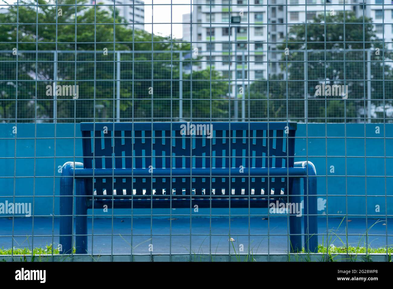 Metal bench behind metal grid Stock Photo - Alamy