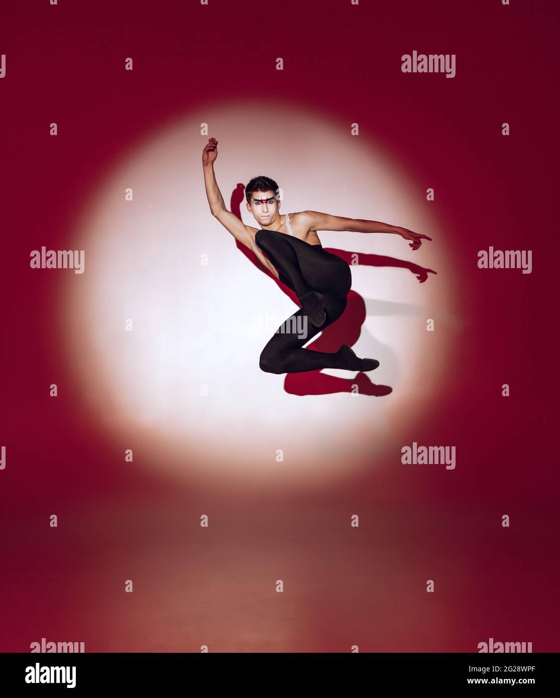 Ballet dancer dancing over red studio background. Modern design ...