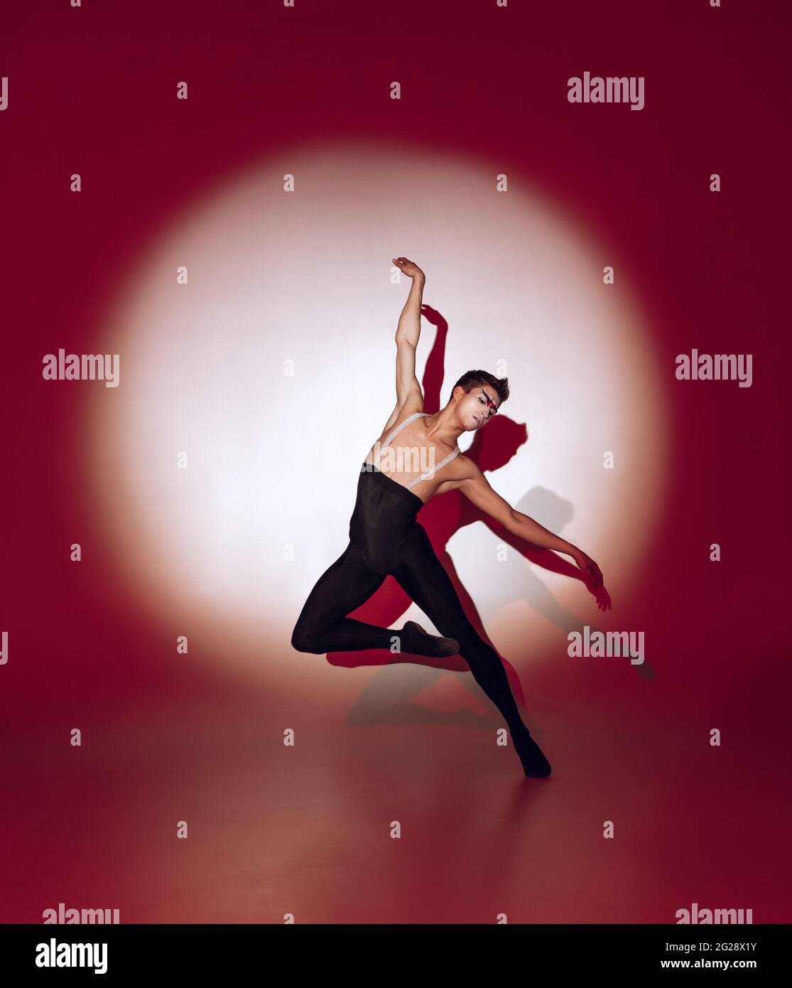 Ballet dancer dancing over red studio background. Modern design ...