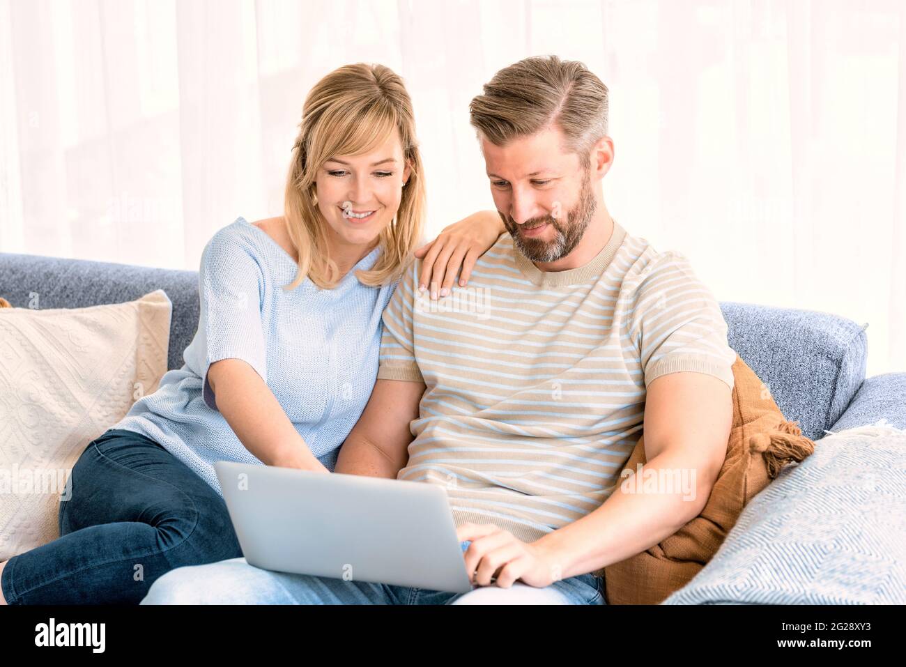 Shot of lovely couple relaxing on the couch at home and using laptop ...