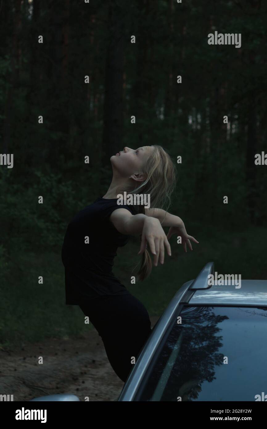 A beautiful blonde girl in black clothes is standing leaning out of the ...