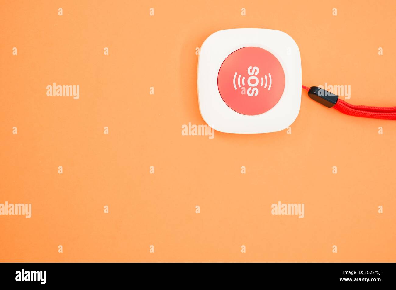 Top view of an SOS button on a string, placed on an orange surface ...