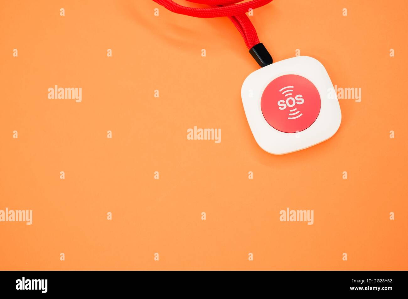 Top view of an SOS button on a string, placed on an orange surface ...