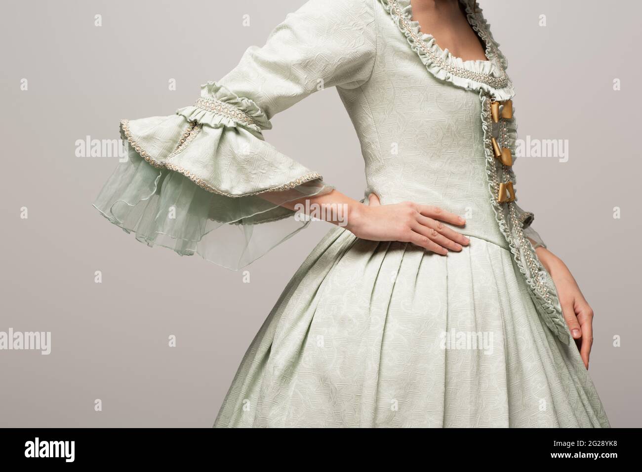 partial view of young woman in retro dress posing with hand on hip ...