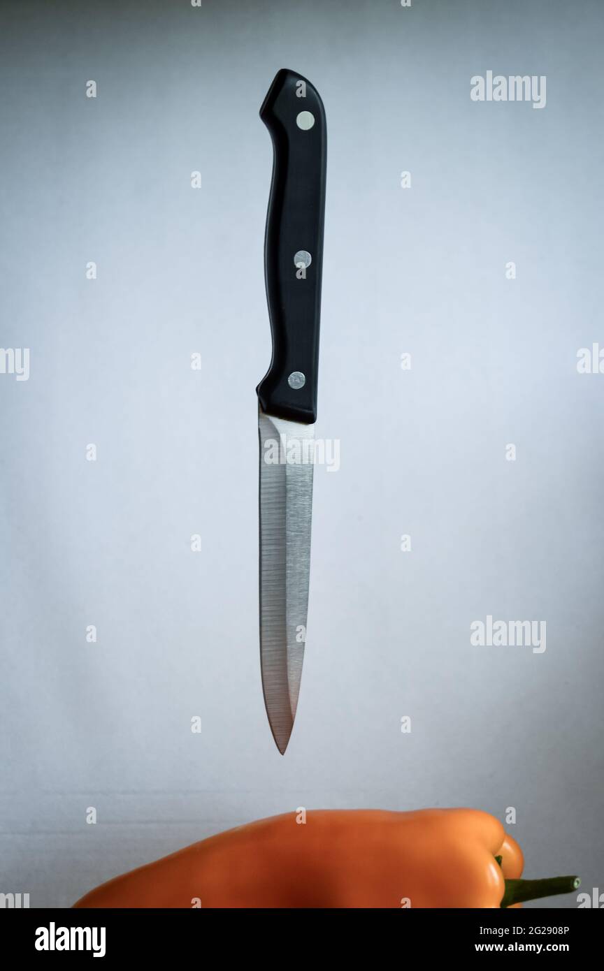 Floating knife over a yellow orange pointed pepper, surrealistic ...