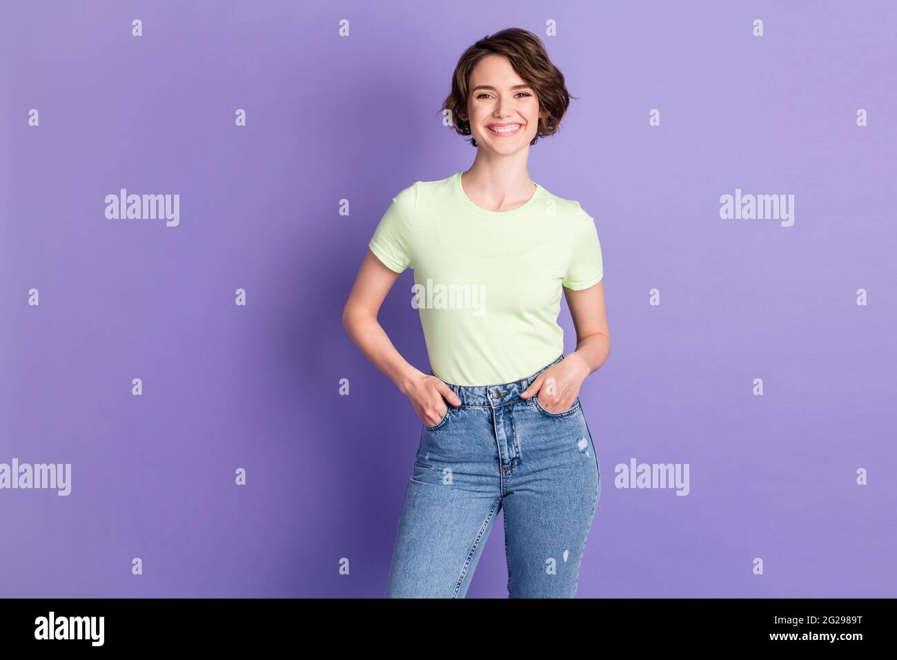 Portrait of attractive cheerful glad girl holding hands in pockets ...