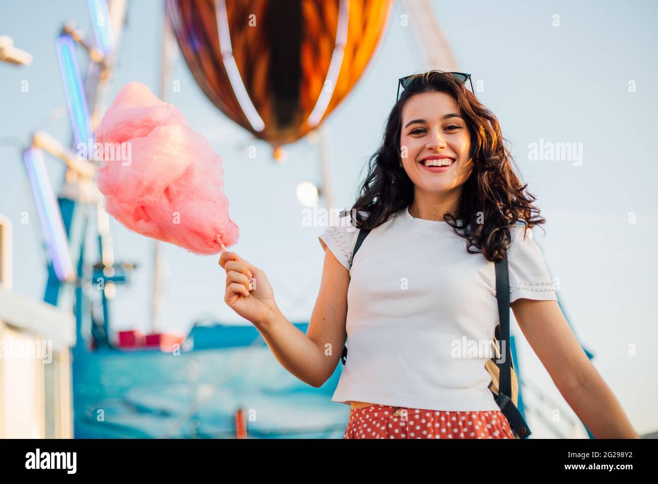 Happy young beautiful woman eating cotton candy at fairground Stock ...