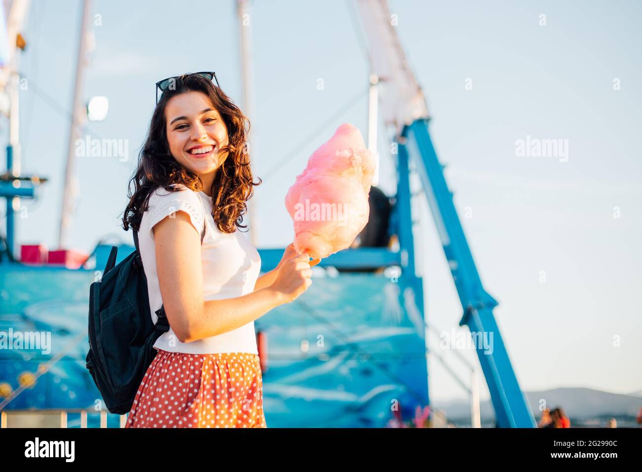 Happy young beautiful woman eating cotton candy at fairground Stock ...