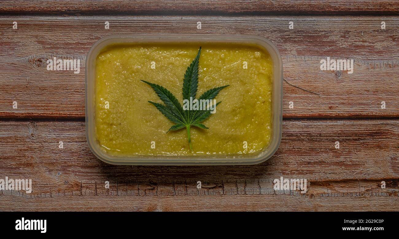 Marijuana butter on wooden table with dark green leafs Stock Photo - Alamy